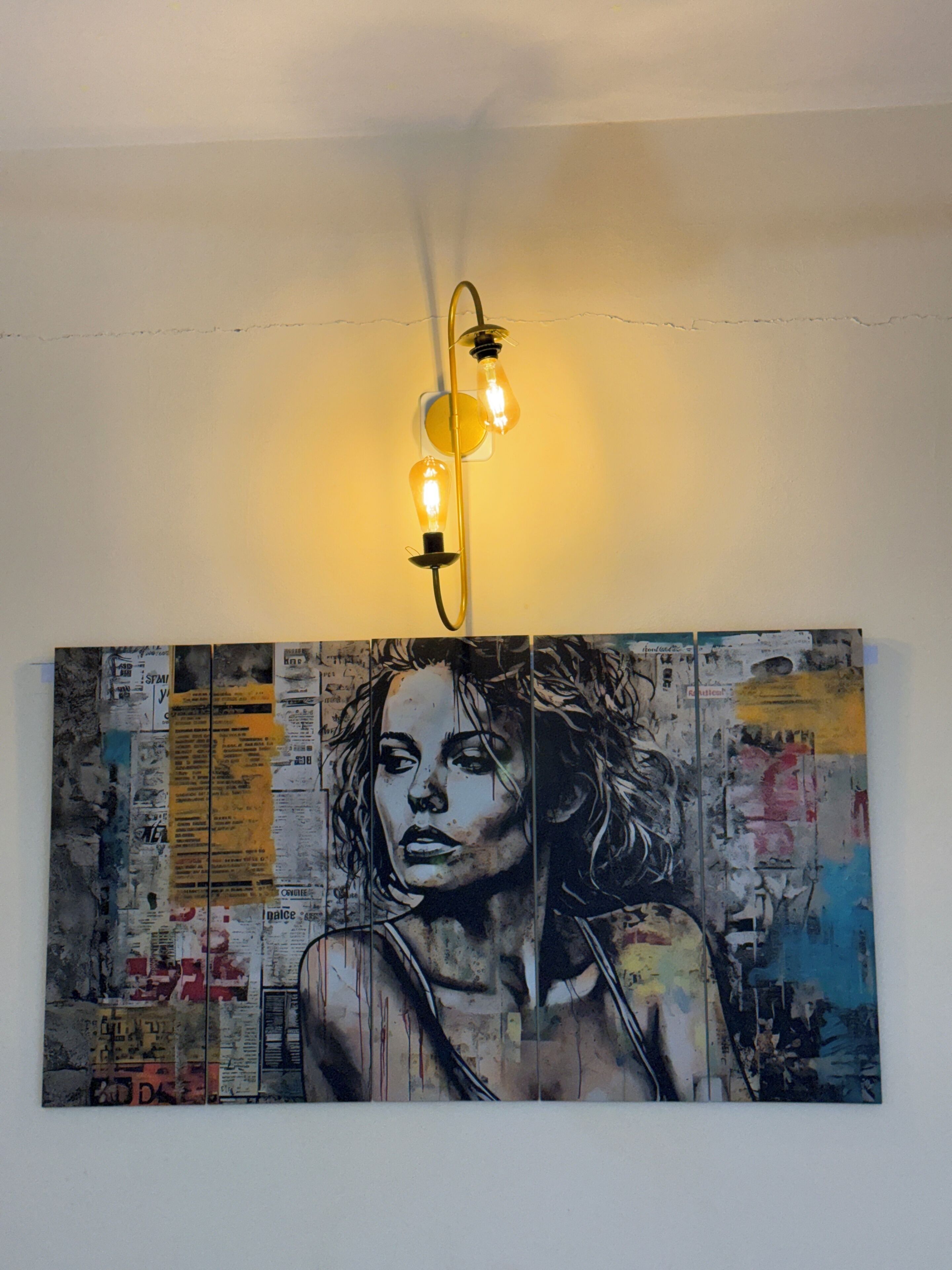 Paredes com uma grande pintura abstrata e um lustre.
