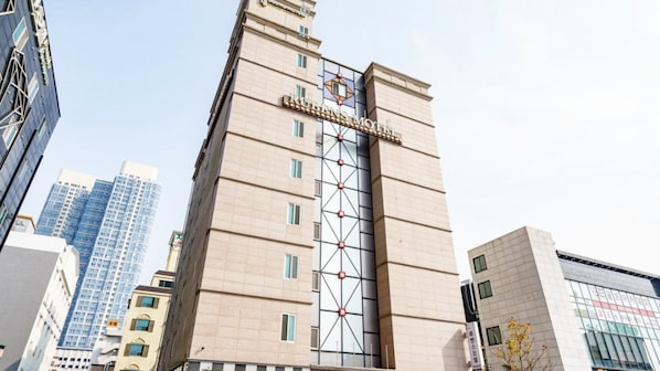 Um edifício de hotel alto com design moderno, exibindo uma placa com o nome em destaque no topo.