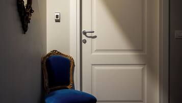 Quarto com porta branca identificada como "B.CHATEAUBRIAND", uma poltrona azul estofada e piso de madeira.