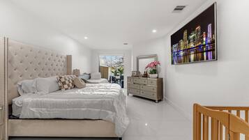 Quarto moderno com uma cama grande, penteadeira e uma pintura de paisagem urbana na parede.