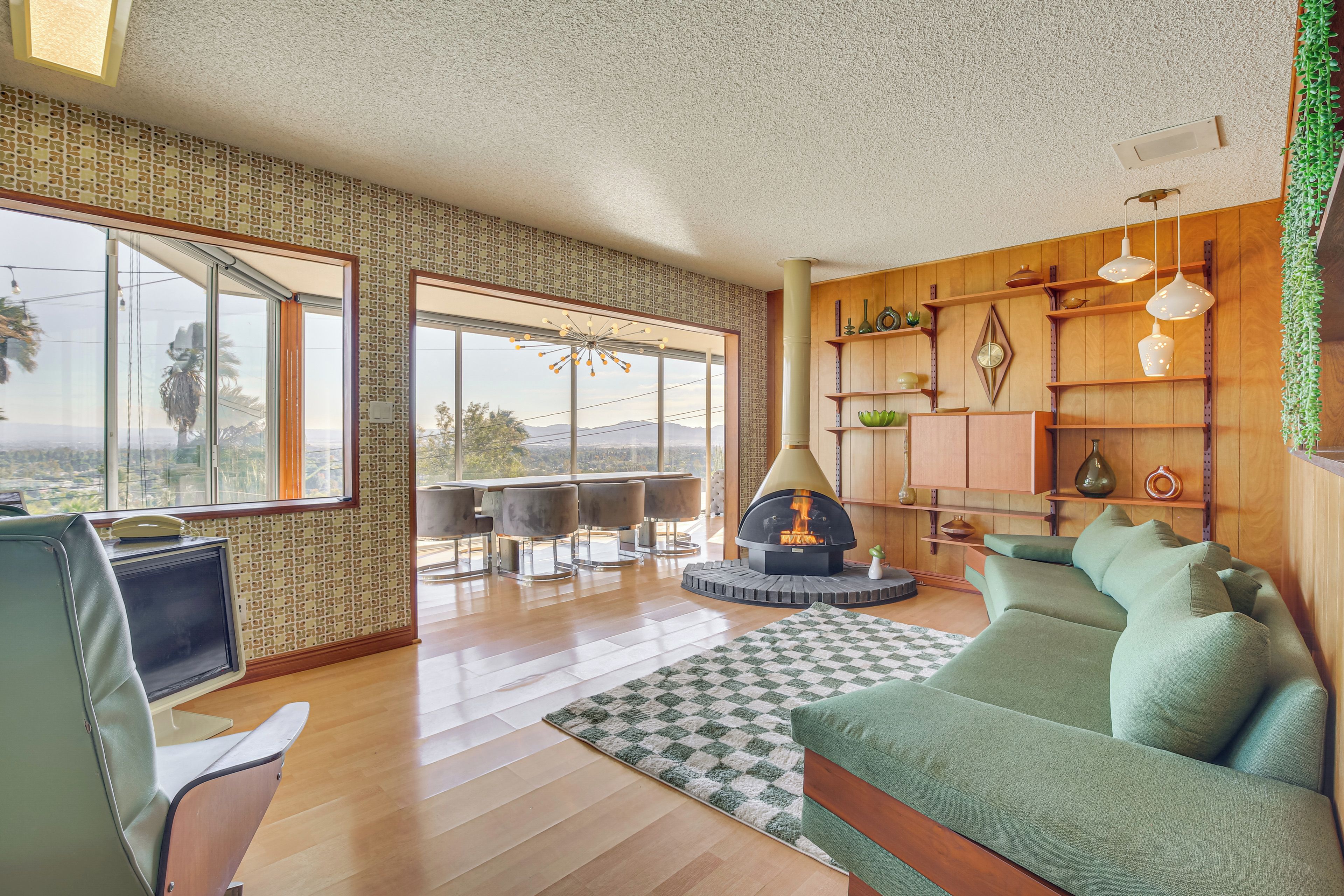 Uma sala de estar moderna com lareira, um sofá, uma televisão e uma área de jantar com vista.