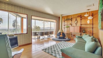 Uma sala de estar moderna com lareira, um sofá, uma televisão e uma área de jantar com vista.