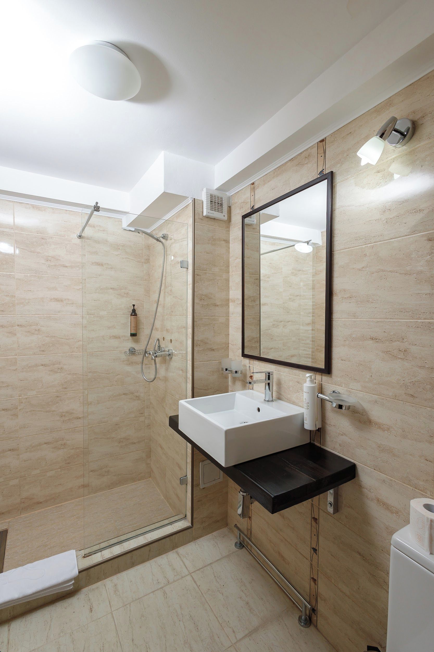 Casa de banho moderna com lavatório branco, espelho grande e cabine de duche.