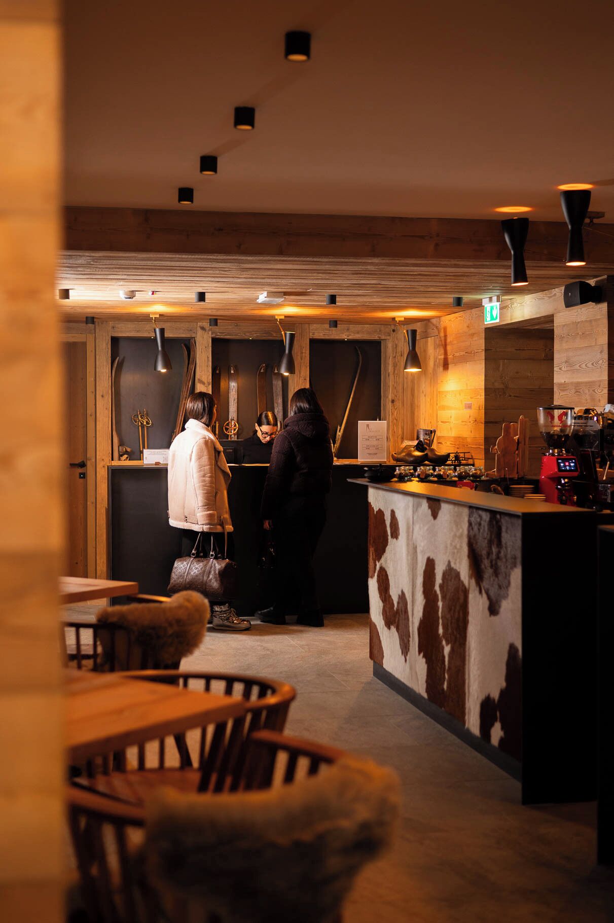 Um espaço de bar acolhedor, com detalhes em madeira, um balcão e área de estar com cadeiras.