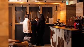 Um espaço de bar acolhedor, com detalhes em madeira, um balcão e área de estar com cadeiras.