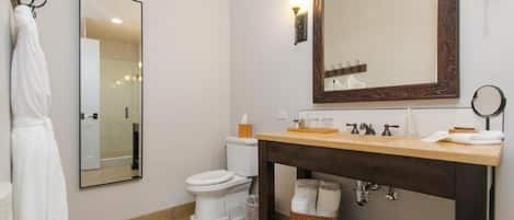 Um banheiro com toucador de madeira, um espelho grande, um porta-toalhas e um vaso sanitário.