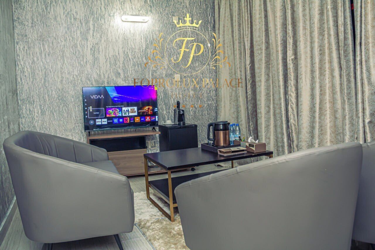 Uma sala de estar moderna com uma televisão de tela plana, uma cafeteira e uma mesa.