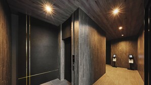 Um interior moderno com piso de madeira, paredes escuras e uma escada.