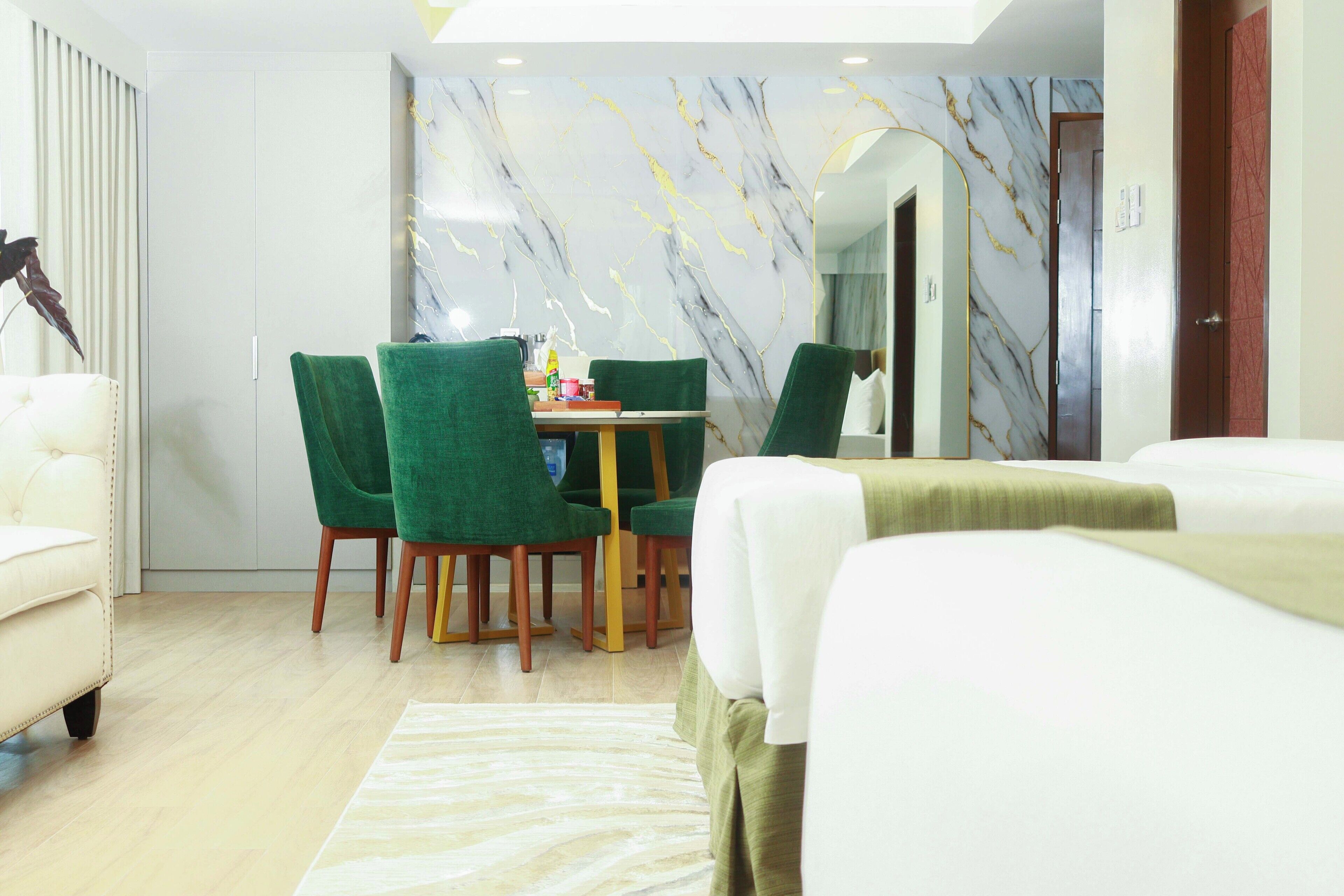 Quarto de hotel com cama, uma mesa de jantar com cadeiras, um espelho e um guarda-roupa.