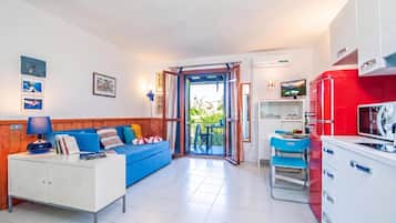Uma sala de estar moderna com um sofá azul, um armário branco e uma geladeira vermelha.
