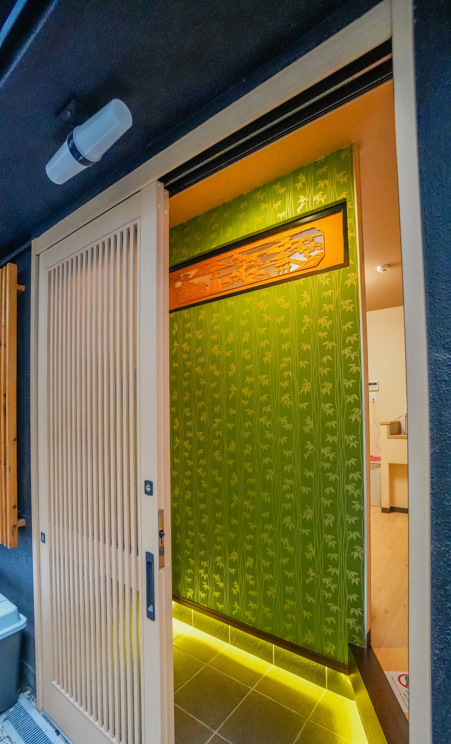 Uma entrada em estilo japonês tradicional, com porta deslizante e painel decorativo.