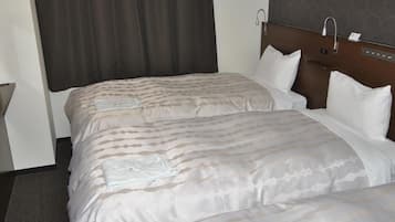 Quarto de hotel com duas camas, cabeceira, cortina e uma pequena mesa.