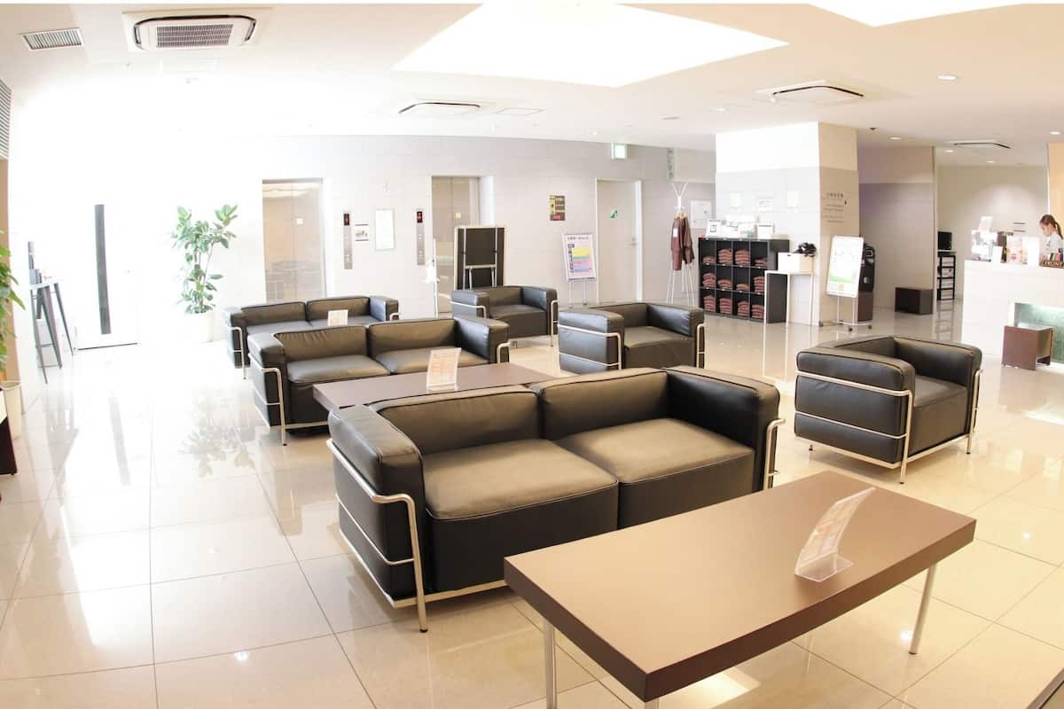 Um saguão de hotel moderno com assentos de couro, um balcão de recepção e piso revestido e impecável.