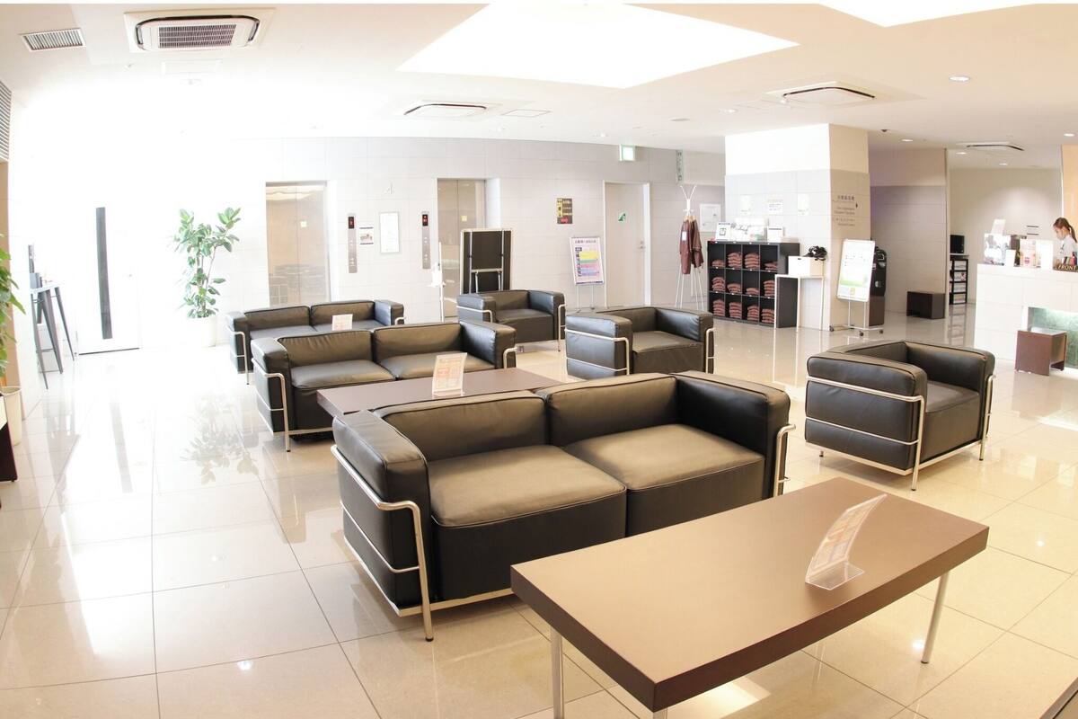 Um saguão de hotel moderno com assentos de couro, um balcão de recepção e piso revestido e impecável.
