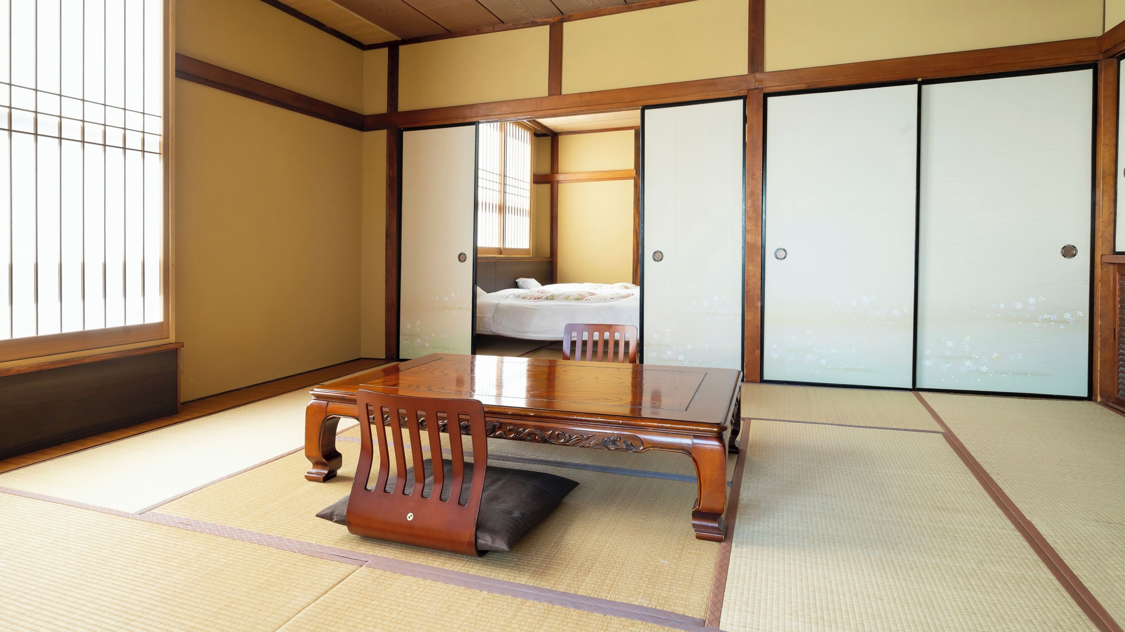 Um quarto japonês tradicional com tatames, uma mesa de madeira e portas deslizantes.