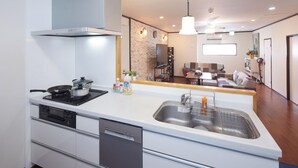 Uma cozinha moderna com fogão embutido, pia e lava-louças. É possível ver uma área de refeições com mesa e cadeiras através da cozinha.