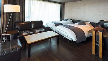 Quarto de hotel com sofá, duas camas, escrivaninha e abajur.