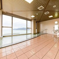 Piscina interior ampla com grandes janelas que oferecem vista para o mar e montanhas.