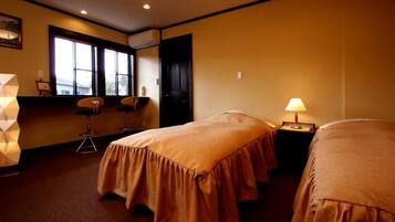 Quarto de hotel com duas camas, uma janela, uma escrivaninha e uma cadeira.