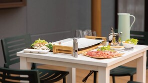 Mesa posta com pratos de comida, um grill portátil e uma jarra.