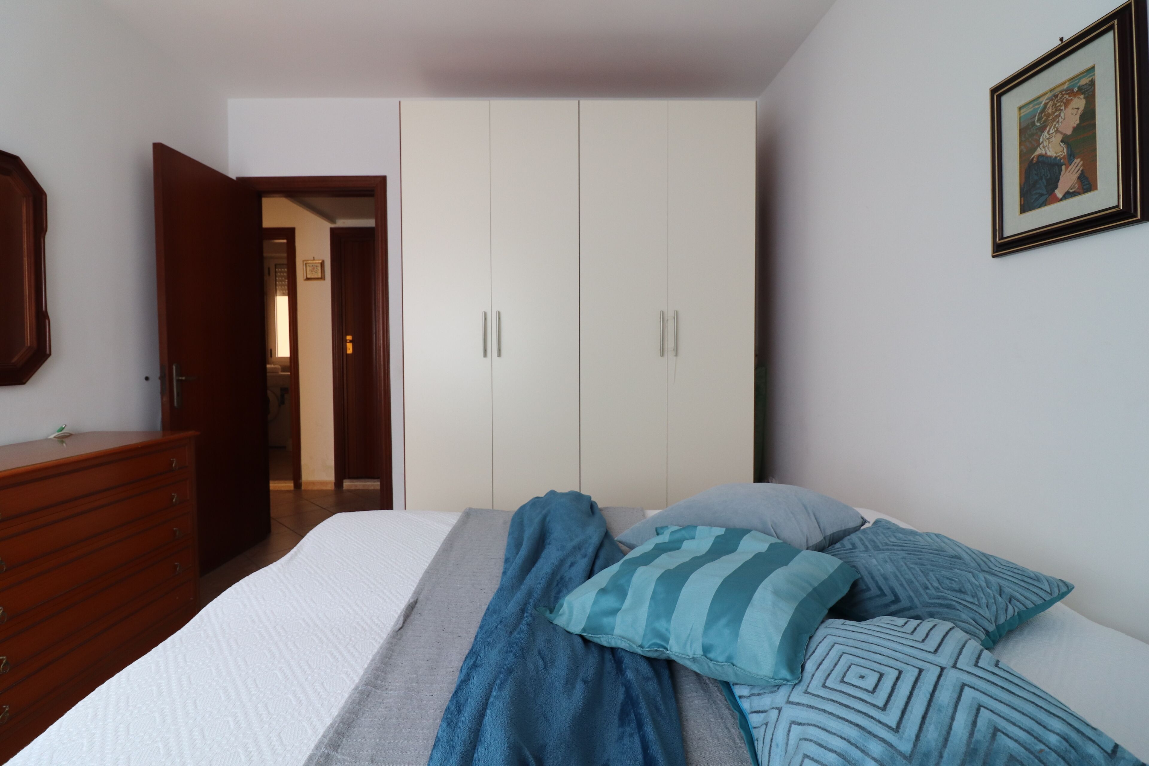 Um quarto com uma cama, cômoda e guarda-roupa.