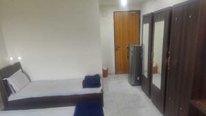 Quarto de hotel com duas camas de solteiro, um guarda-roupa, um frigorífico e uma porta.