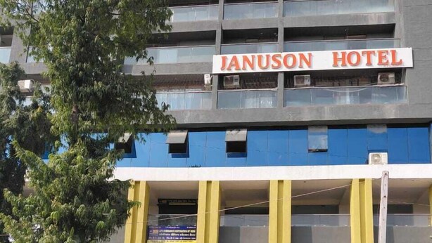 Fachada do Hotel Januson com uma placa, um Jeep estacionado em frente e plantas em vasos na entrada.