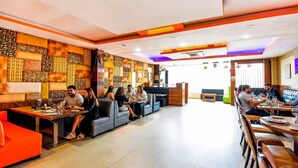 Um restaurante com várias áreas de estar, incluindo mesas e sofás, e um design de parede estampado.