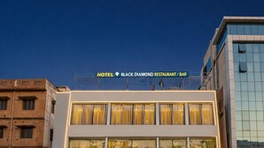 Um hotel com fachada moderna, grandes janelas e uma placa indicando que abriga um restaurante e bar.