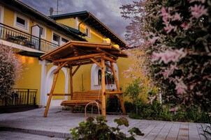 Um conjunto de baloiço de madeira em frente a um edifício amarelo com varanda.