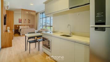 Cozinha moderna com forno embutido, micro-ondas e frigorífico. Dispõe de área de refeições com mesa e cadeiras.