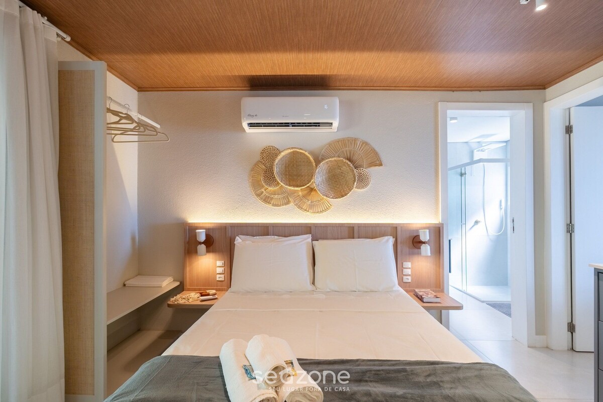 Quarto de hotel moderno com uma cama grande, ar condicionado fixado na parede e um elemento decorativo na parede.