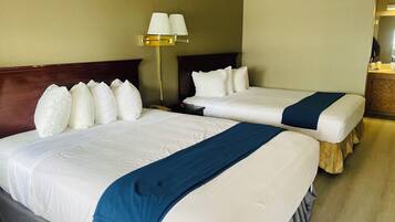 Quarto de hotel com duas camas, uma mesa de cabeceira, uma luminária e cabeceira de madeira.