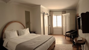 Quarto com cama grande, escrivaninha, cadeira, guarda-roupa e janela.