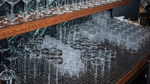 Uma área de bar com várias prateleiras de copos e garrafas de vinho.