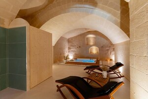 Um quarto de spa com piso de madeira, mesa de massagem, cadeira de massagem e banheira de hidromassagem.