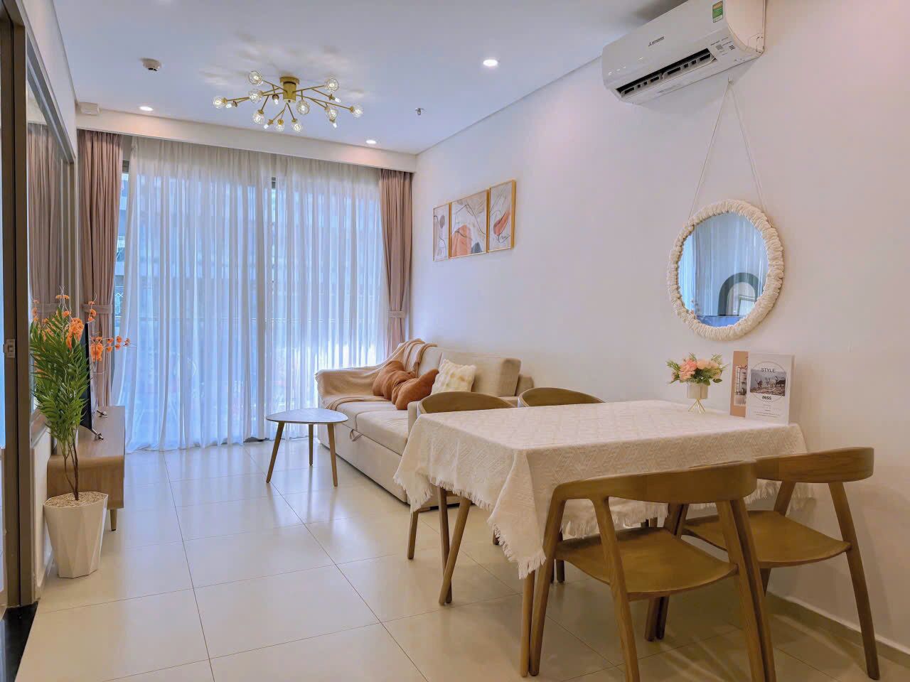 Uma sala de estar moderna com sofá, mesa de jantar, cadeiras e uma grande janela com cortinas.