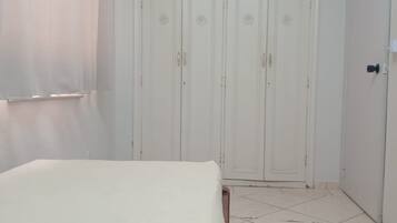 Quarto com cama, guarda-roupa e porta.