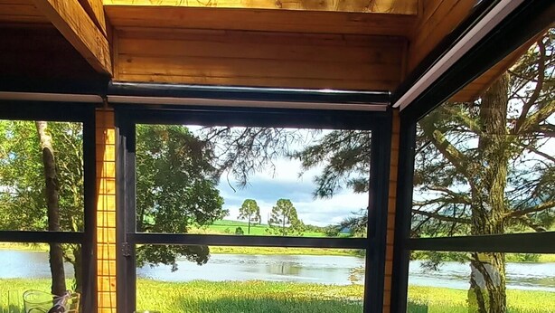 Uma banheira de hidromassagem em uma cabana de madeira com vista para um lago e árvores.