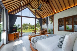 Quarto com uma cama grande, televisão e escrivaninha com cadeiras.