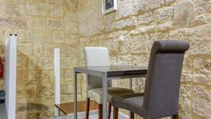 Uma área de refeições com parede de pedra, uma mesa e duas cadeiras.