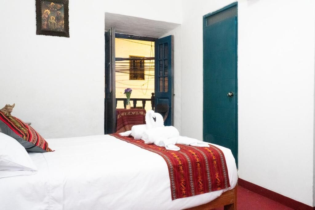 Quarto de hotel com uma cama, uma porta azul e uma varanda com vista.