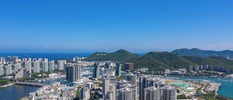 Área urbana com arranha-céus, edifícios residenciais densos, uma marina e montanhas ao fundo.