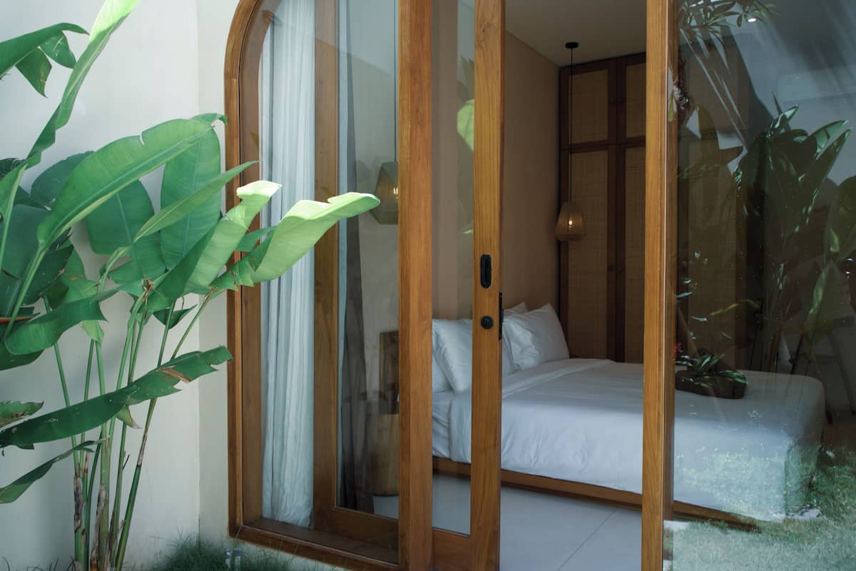 Quarto com cama, janela e uma planta.