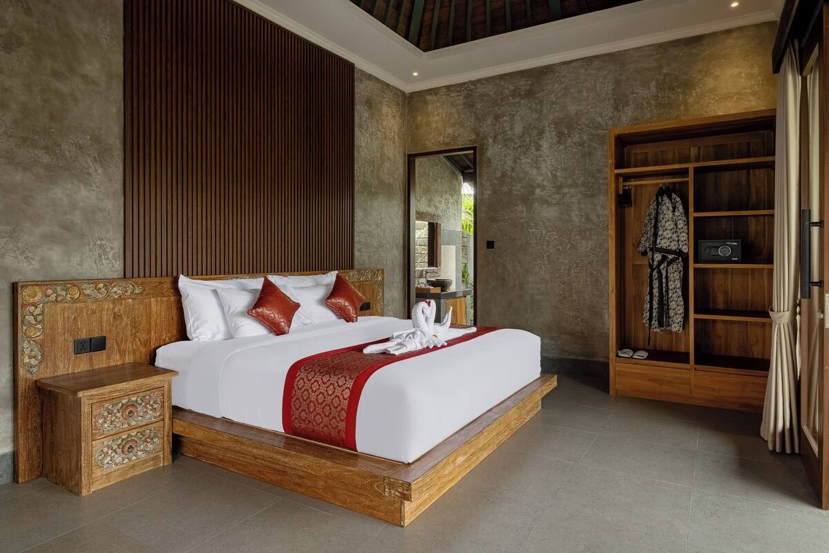 Um quarto espaçoso com uma cama grande, cabeceira de madeira e um guarda-roupa embutido.