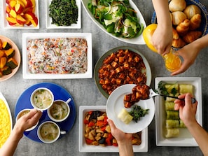Diversos pratos sobre a mesa, incluindo saladas, sopas e um assado.