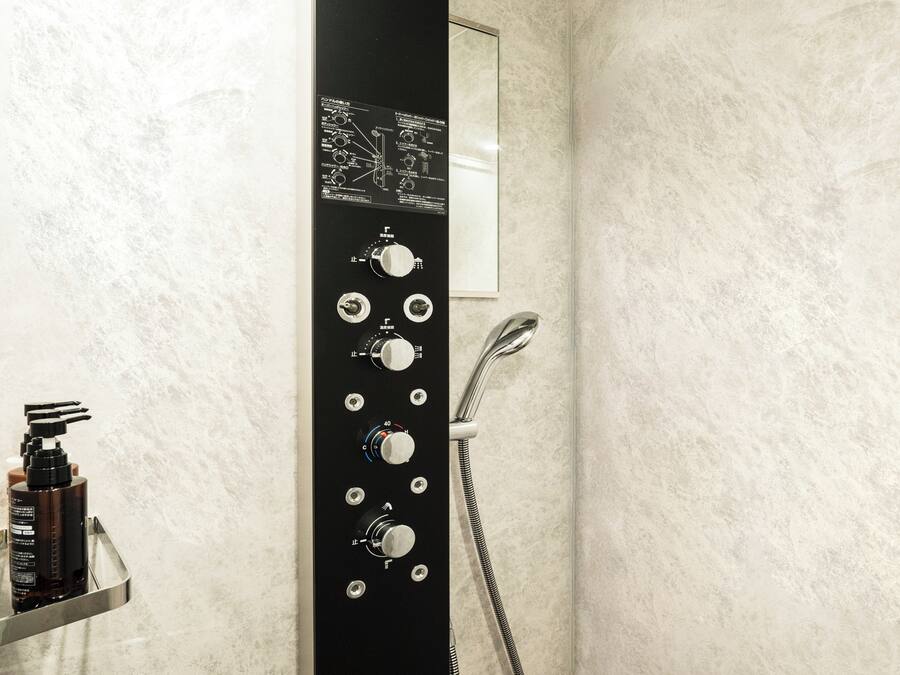 Casa de banho moderna com painel de comando vertical, chuveiro manual e sistema de ventilação integrado.