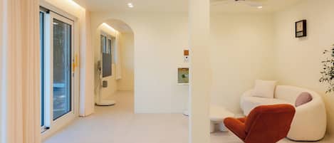 Um interior moderno com um sofá branco, uma poltrona vermelha e um ventilador de teto.