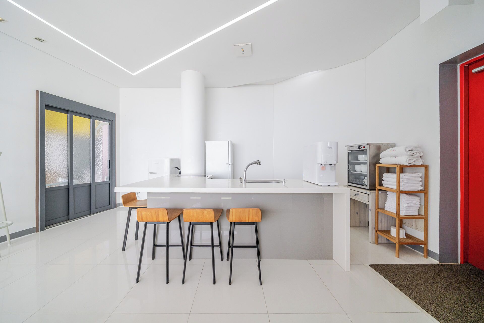 Uma cozinha moderna com uma ilha central, banquetas, uma máquina de café e um porta-toalhas.