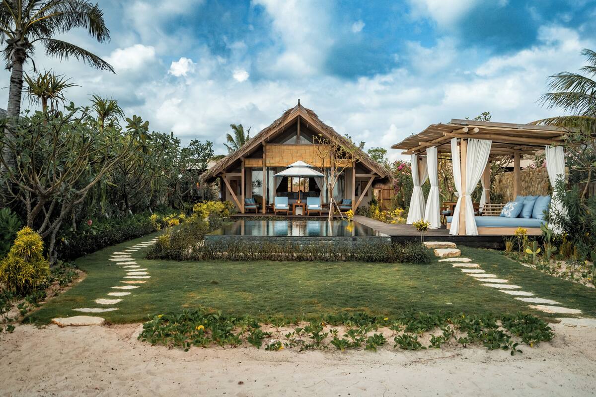 Um resort com piscina, área de estar coberta e vegetação tropical exuberante.